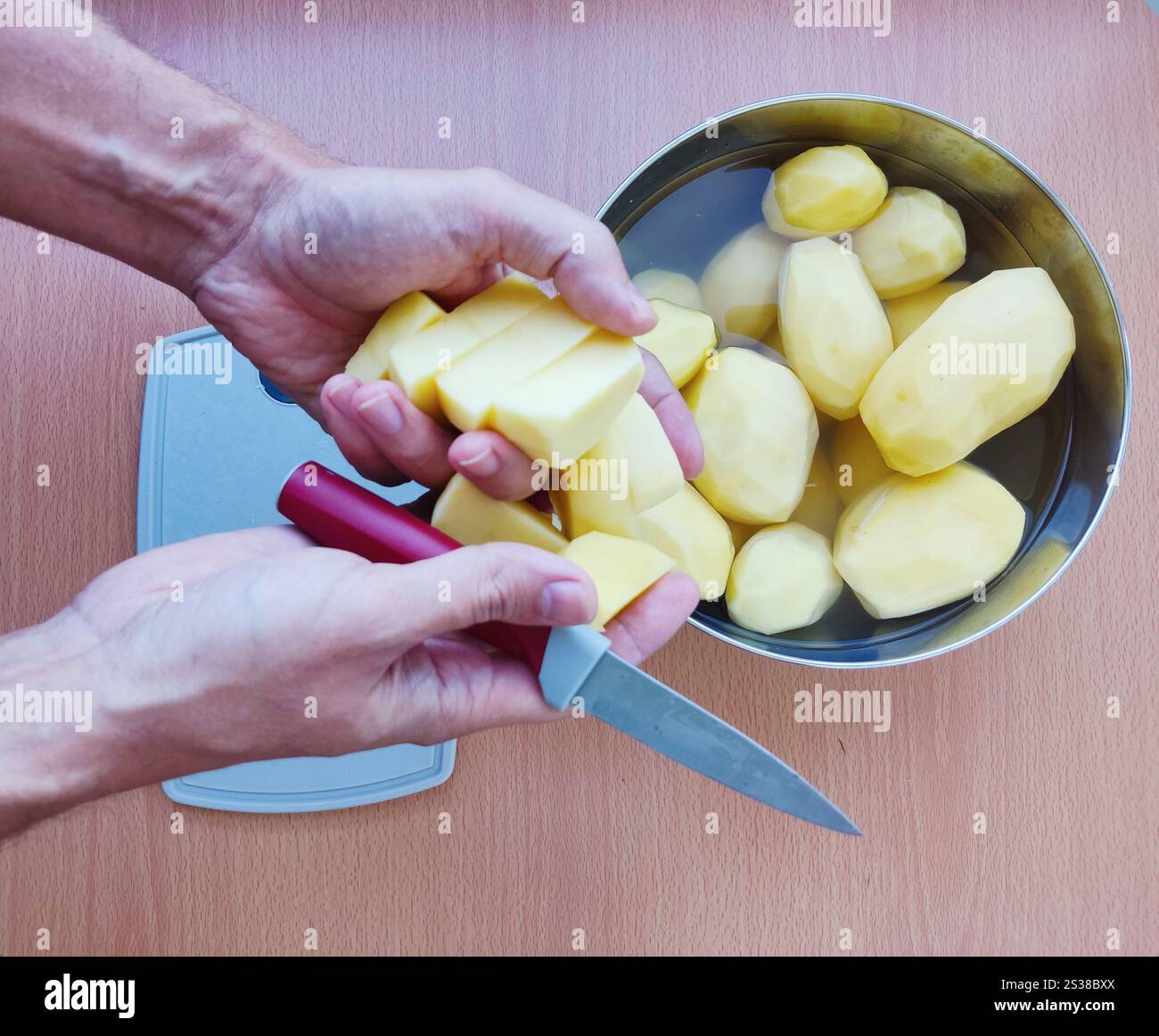 Man holding and peeling potato. Hands cutting potatoes at kitchen to ...
