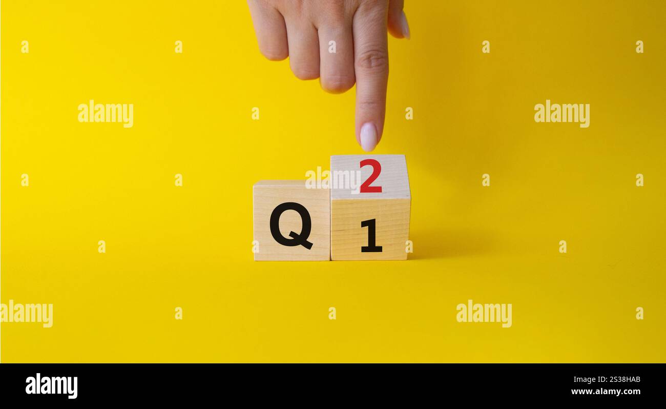 From 1st Quarter to 2nd symbol. Businessman hand points at turned wooden cubes with words 1st ...