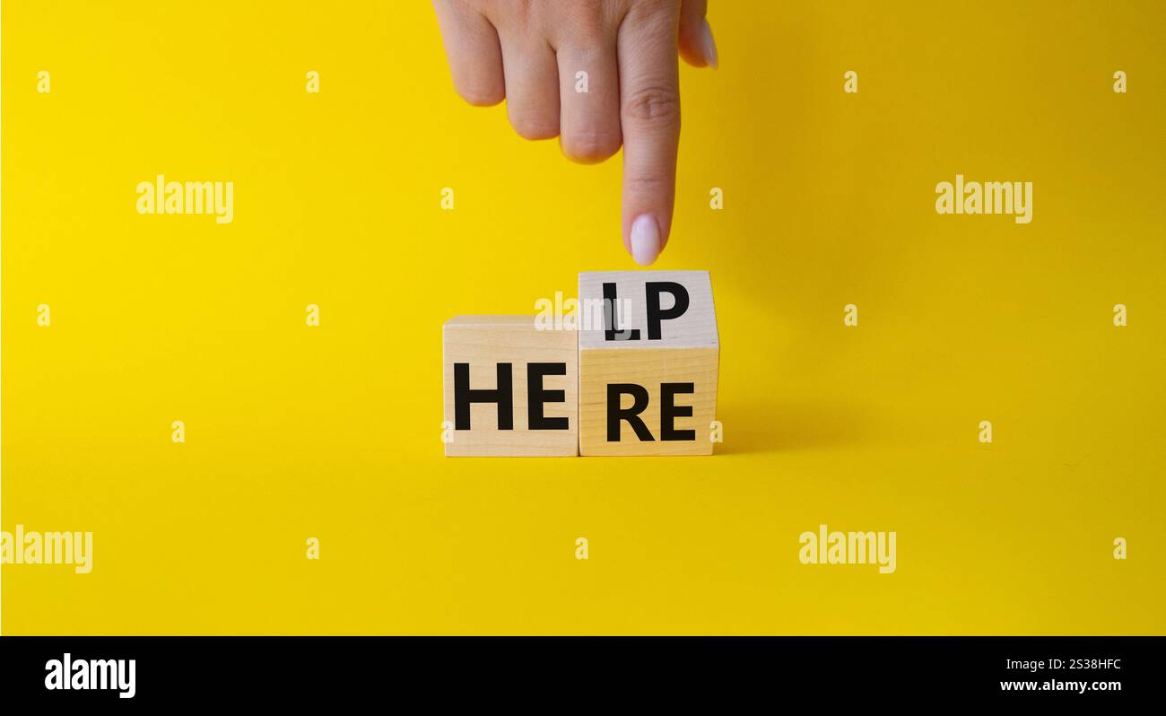 Help is here symbol. Businessman hand points at turned wooden cube with ...