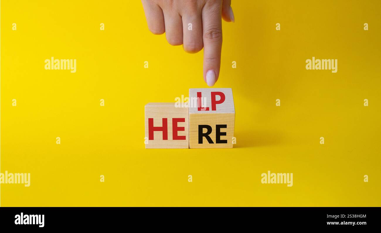 Help is here symbol. Businessman hand points at turned wooden cube with ...