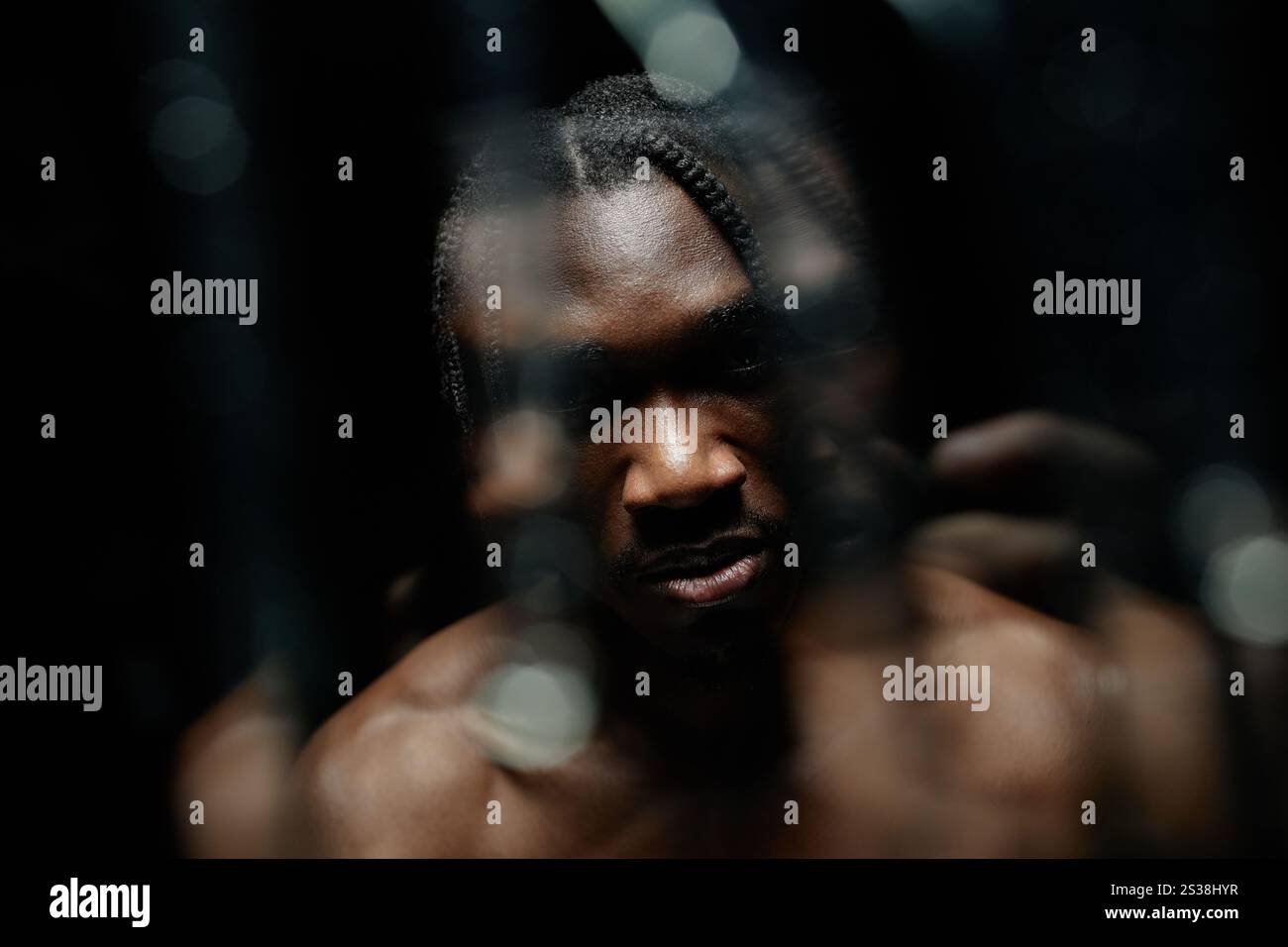 Shot through glass with water running down of Black man staring at ...