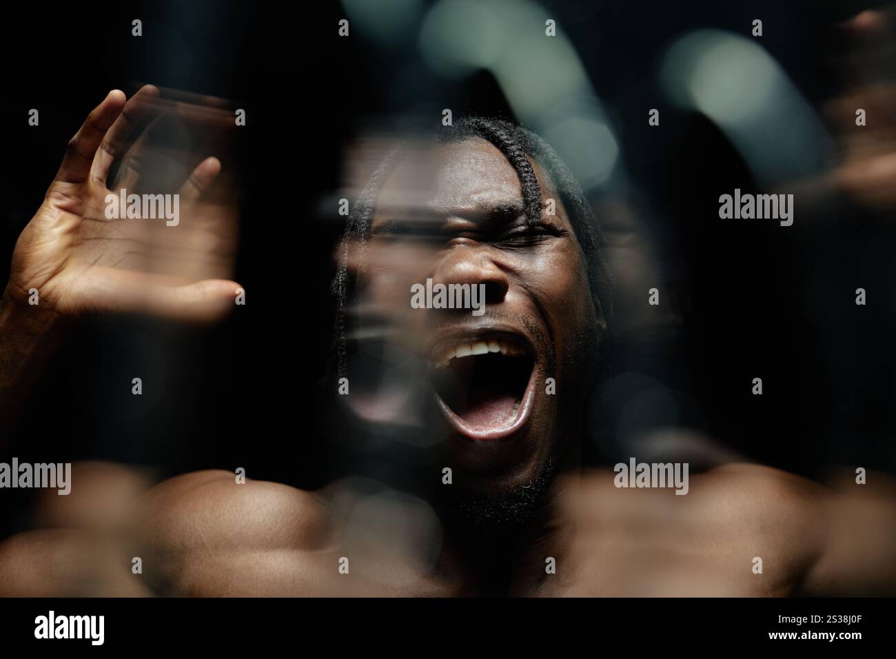Portrait of desperate Black man fiercely shouting with raised hands ...