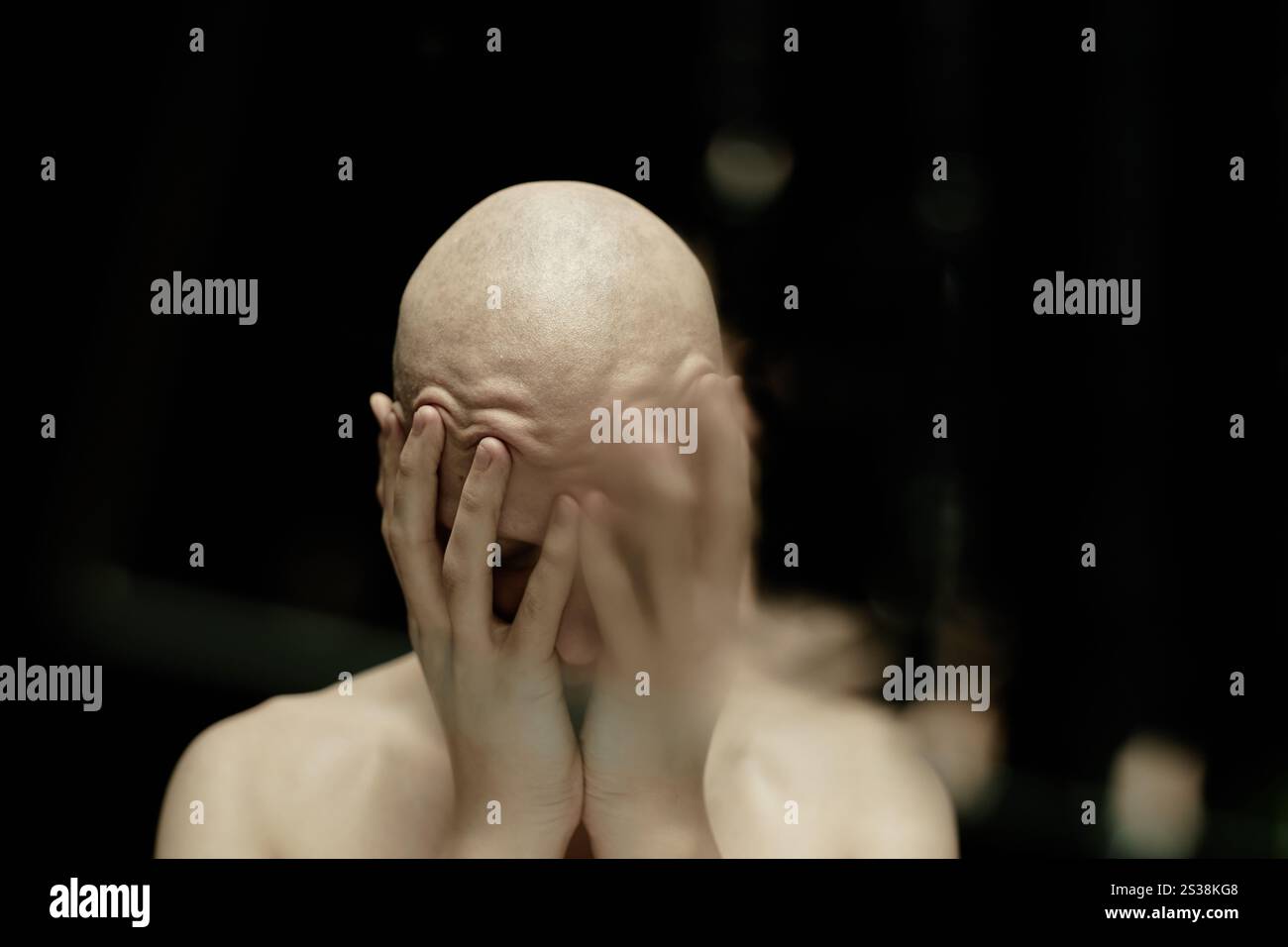 Distorted by water image of pale bald man covering face with hands in ...