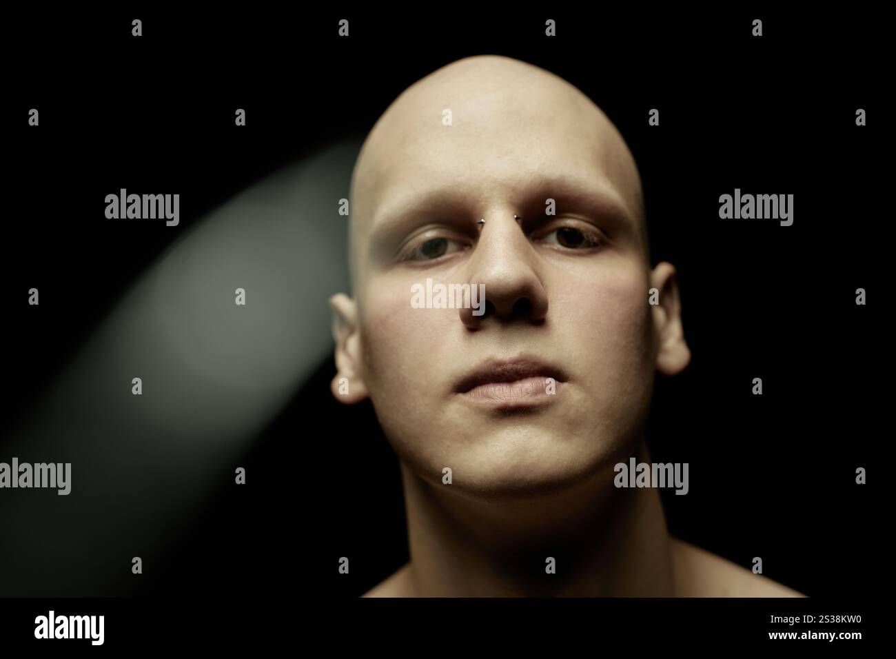 Close up portrait of unemotional pale man with bald head looking down ...