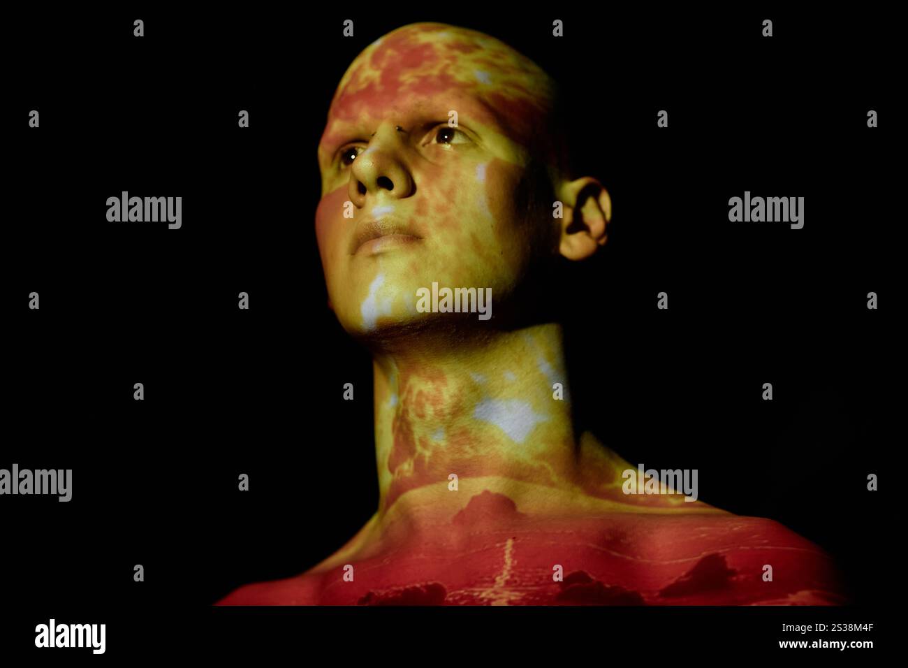 Portrait of bald black eyed man with detached look standing in light of ...