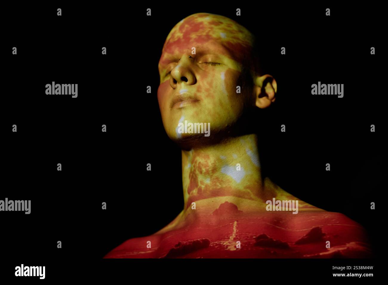 Portrait of man with eyes closed standing in light of projector ...