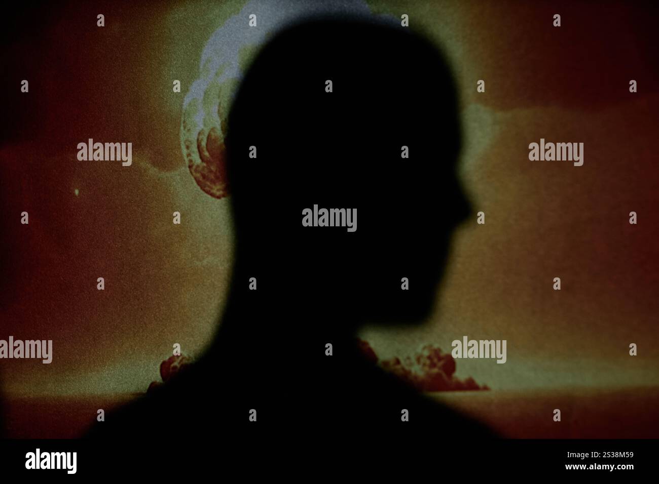 Abstract image of mans head shadow against projection of mushroom cloud ...