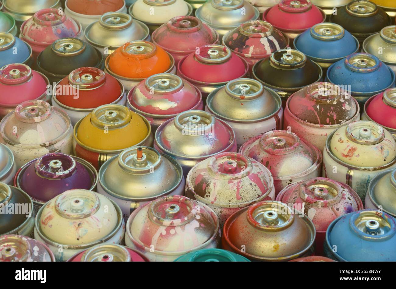 Large number of used colorful spray cans of aerosol paint lying on the ...