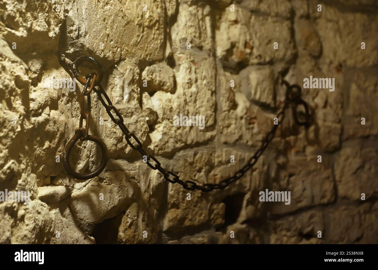 Slavery and bondage strong steel old shackles on stone wall in castle ...