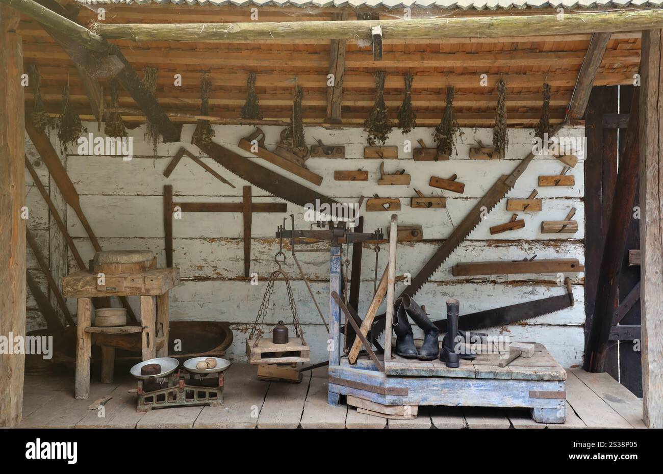 Collection of planers and retro wood saws hang on a wooden wall near an ...