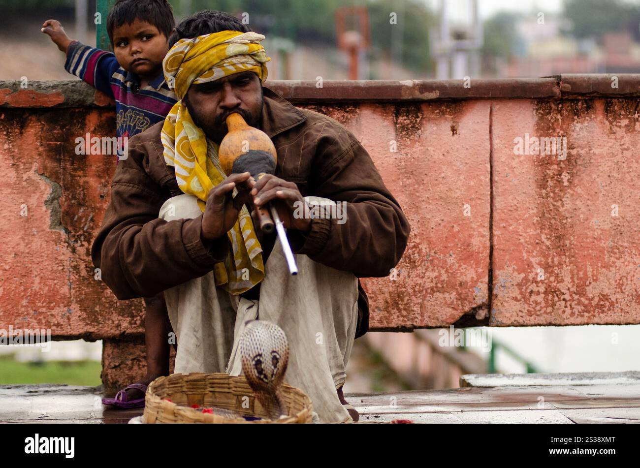 Street performer playing music with a flute while a child looks on in a ...