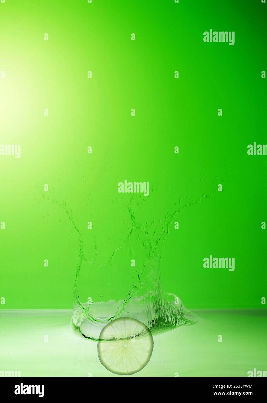 Fresh lime slice creates a dynamic splash in water against a vivid ...