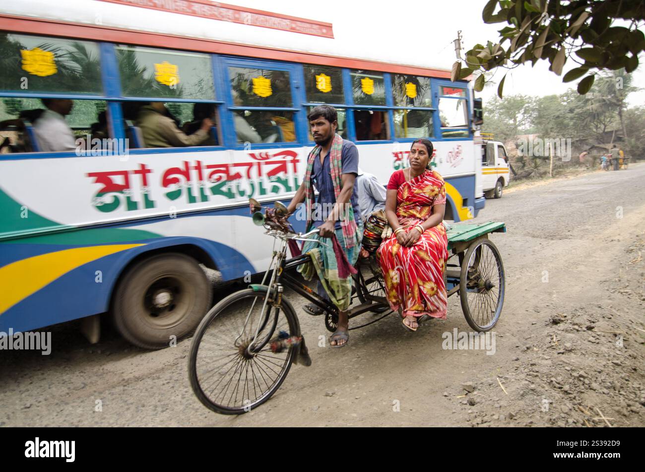 Busy road scene with cyclist transporting a woman on a rickshaw ...