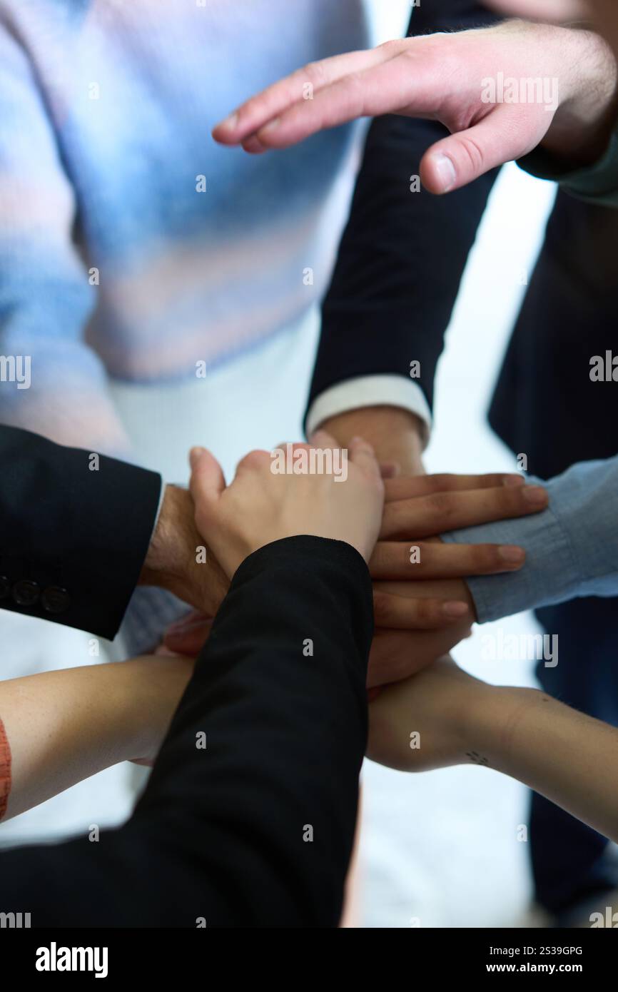 A top view of business people joining hands in a circle, symbolizing ...