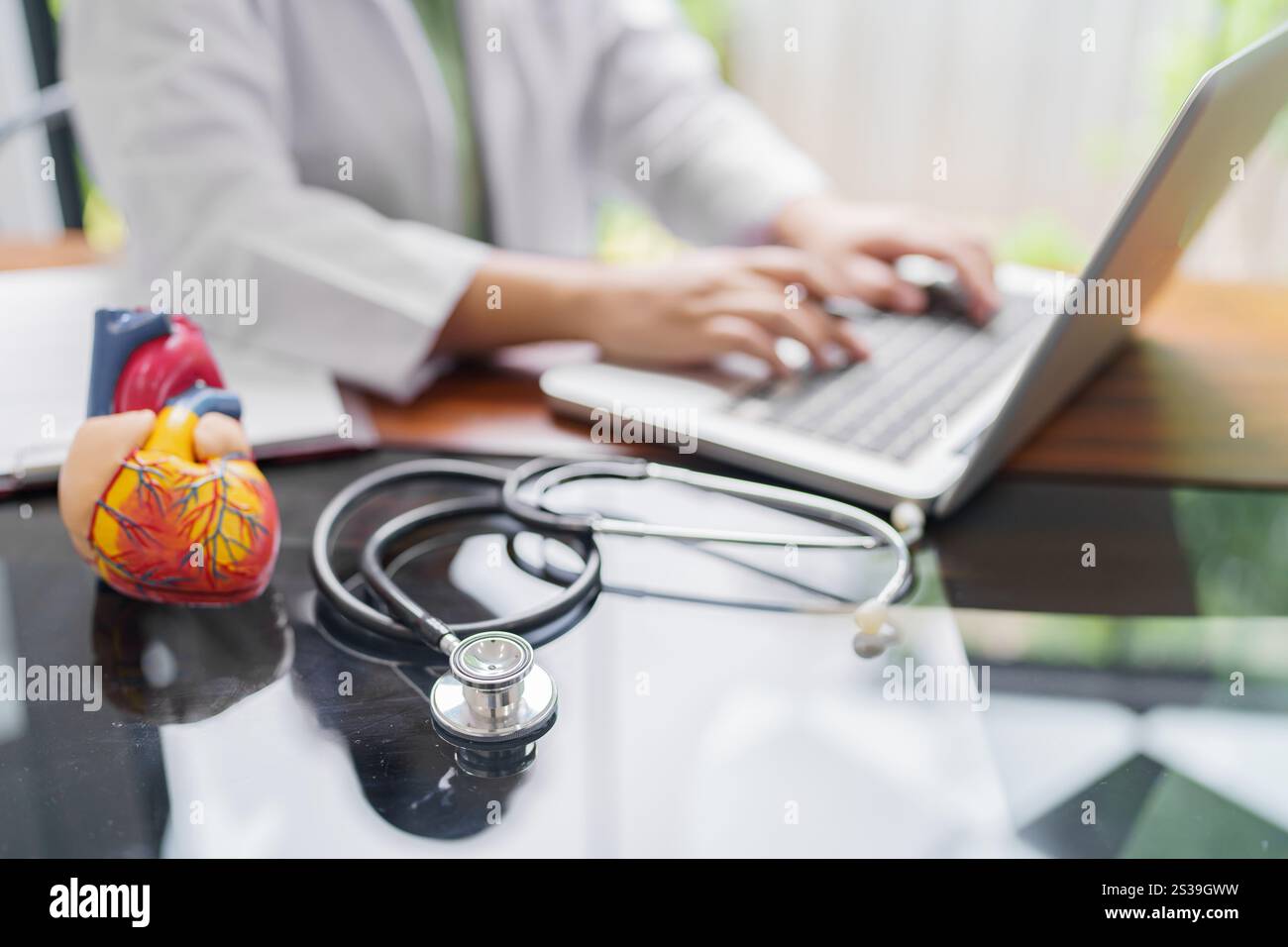 Doctor consult patient on laptop with anatomical model of human heart ...
