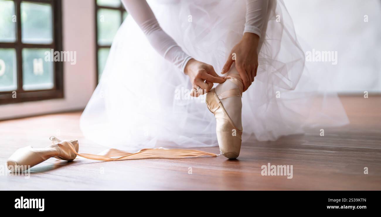 Ballerina in ballet shoes. Asian girl tying ribbons of toe shoes ...