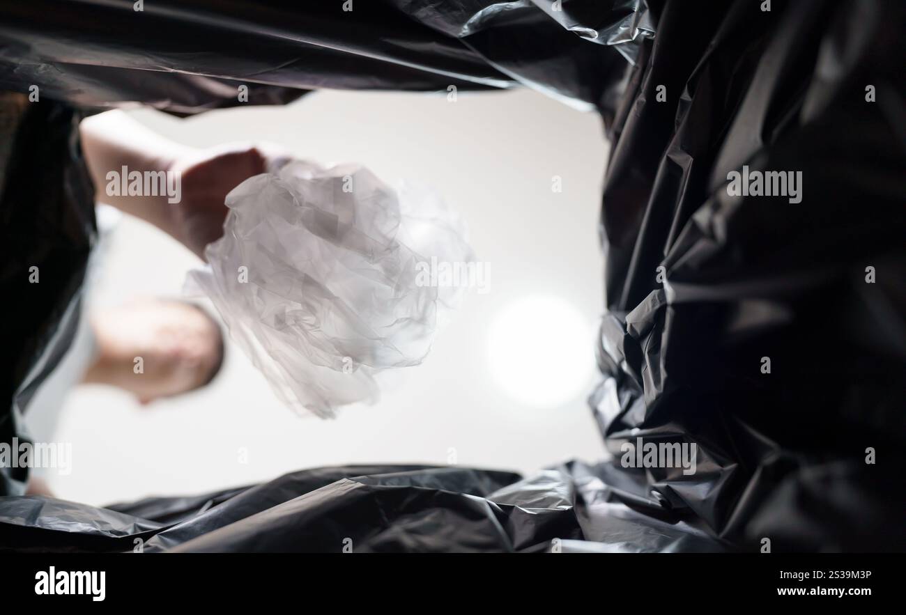 Image from inside black recycling bag of man throwing empty plastic ...