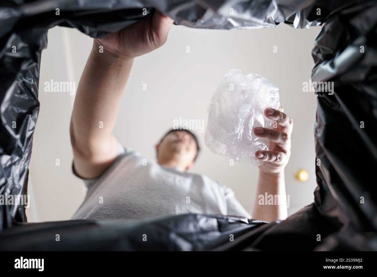 Image from inside black recycling bag of man throwing empty plastic ...