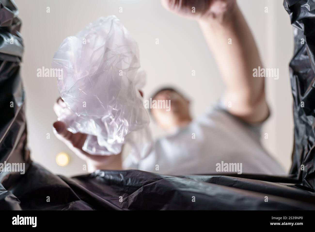 Image from inside black recycling bag of man throwing empty plastic ...