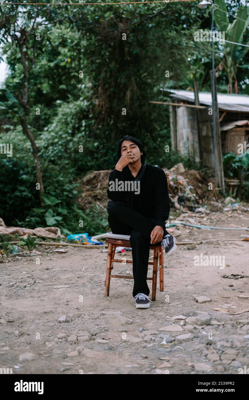 A Southeast Asian man sitting alone on a chair, smoking looks bad Stock ...
