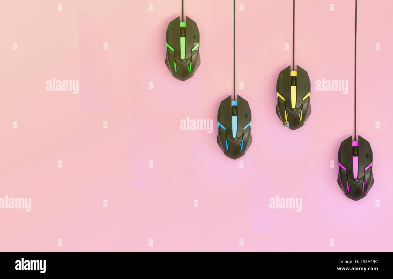 Several computer mice hang on a pastel pink background. The concept of ...