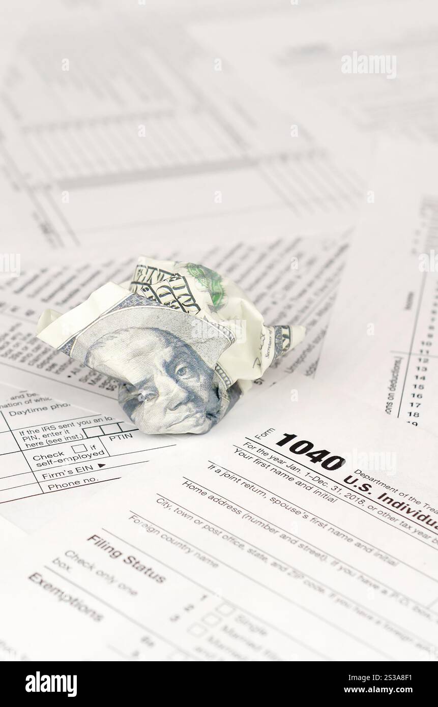 1040 Individual income tax return form and crumpled hundred dollar bill ...