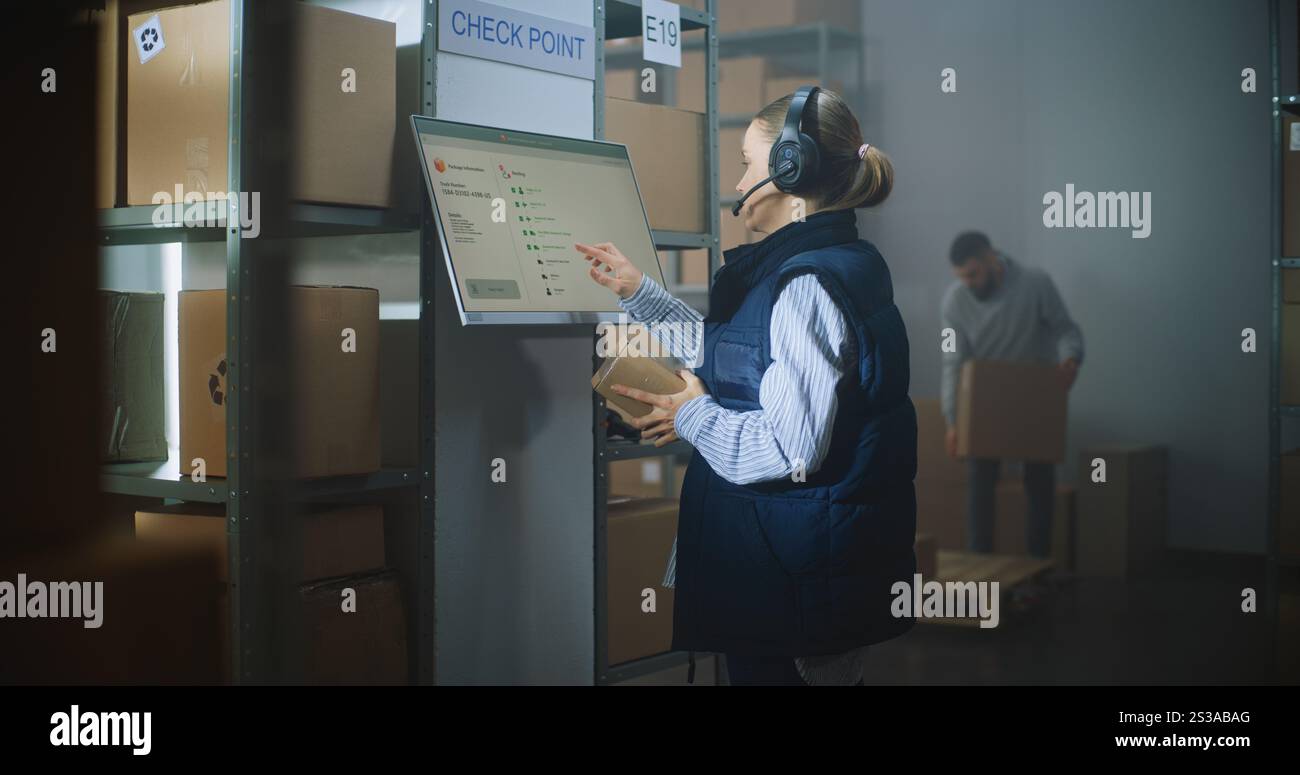Female Logistics Specialist Wearing Headset Scans Cardboard Box at Postal Terminal with Digital ...