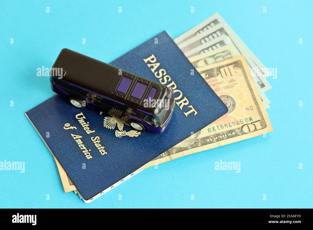 Blue United States of America passport with money and toy bus on blue ...