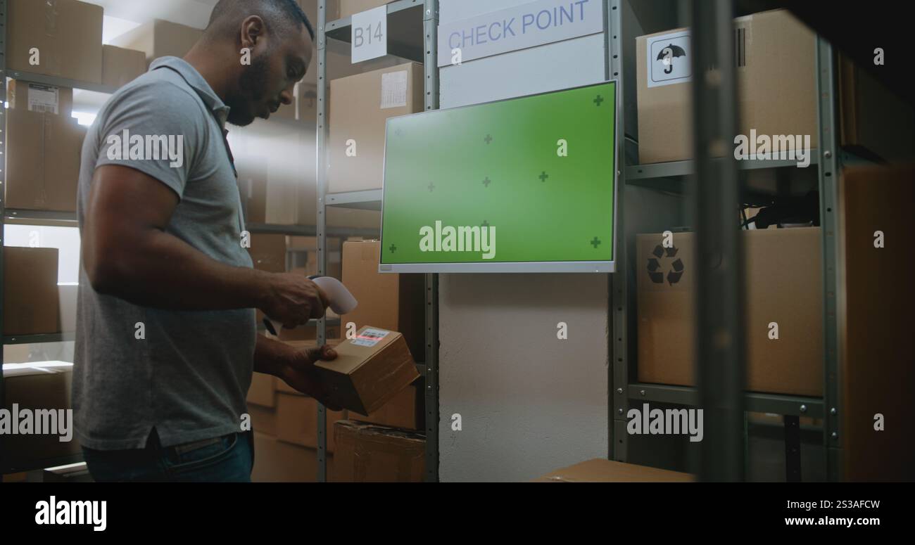African American Warehouse Associate Scans Code on Cardboard Box with Scanner, Checks Parcel ...
