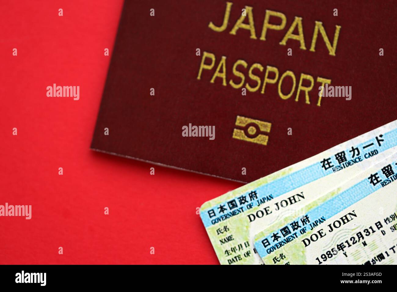 Green residence card of Japan with passport on red background close up ...