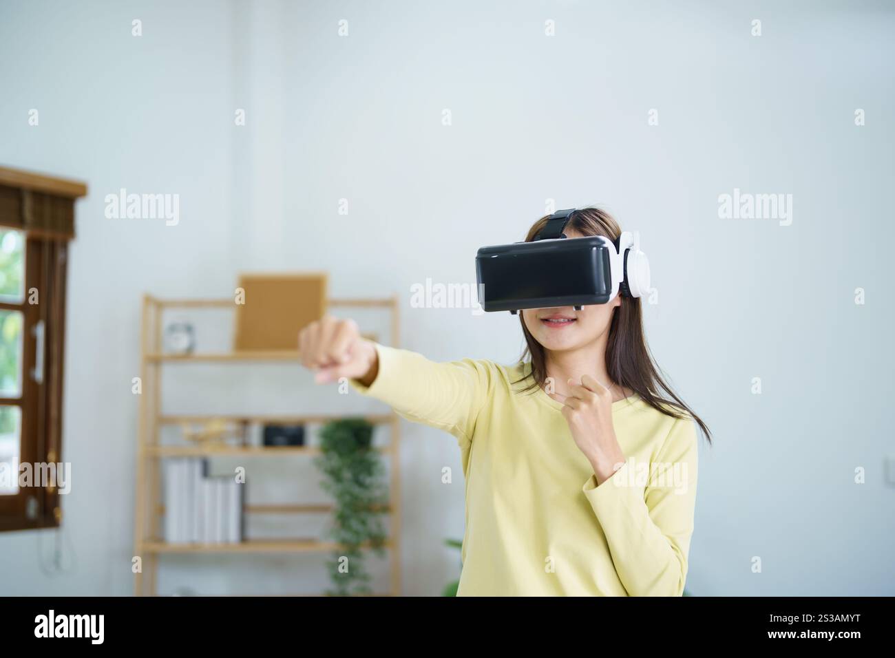 Young Asian woman gamer wearing virtual reality touching air during the VR experience Future ...