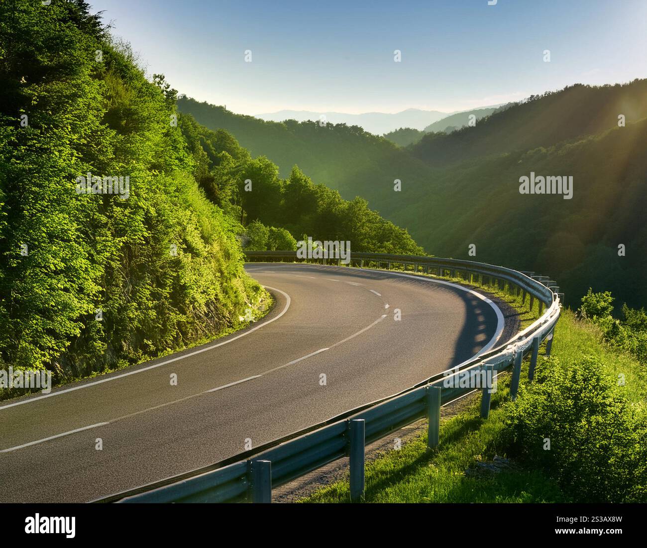 A winding road stretches through a mountainous region, bathed in the ...