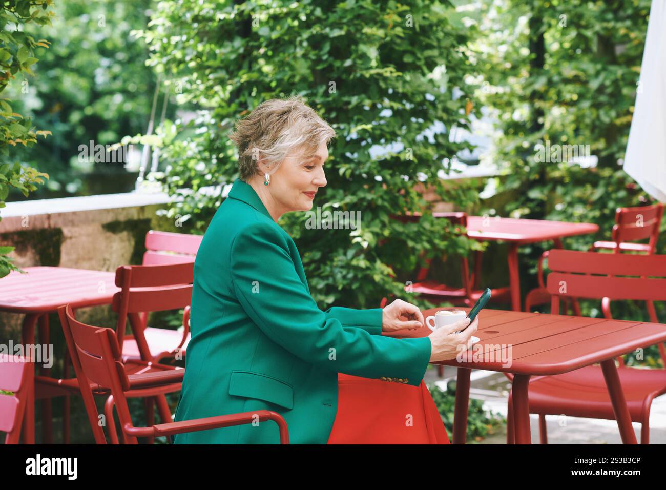 Outdoor portrait of pretty middle age 55 - 60 year old woman relaxing in cafe using phone Stock ...