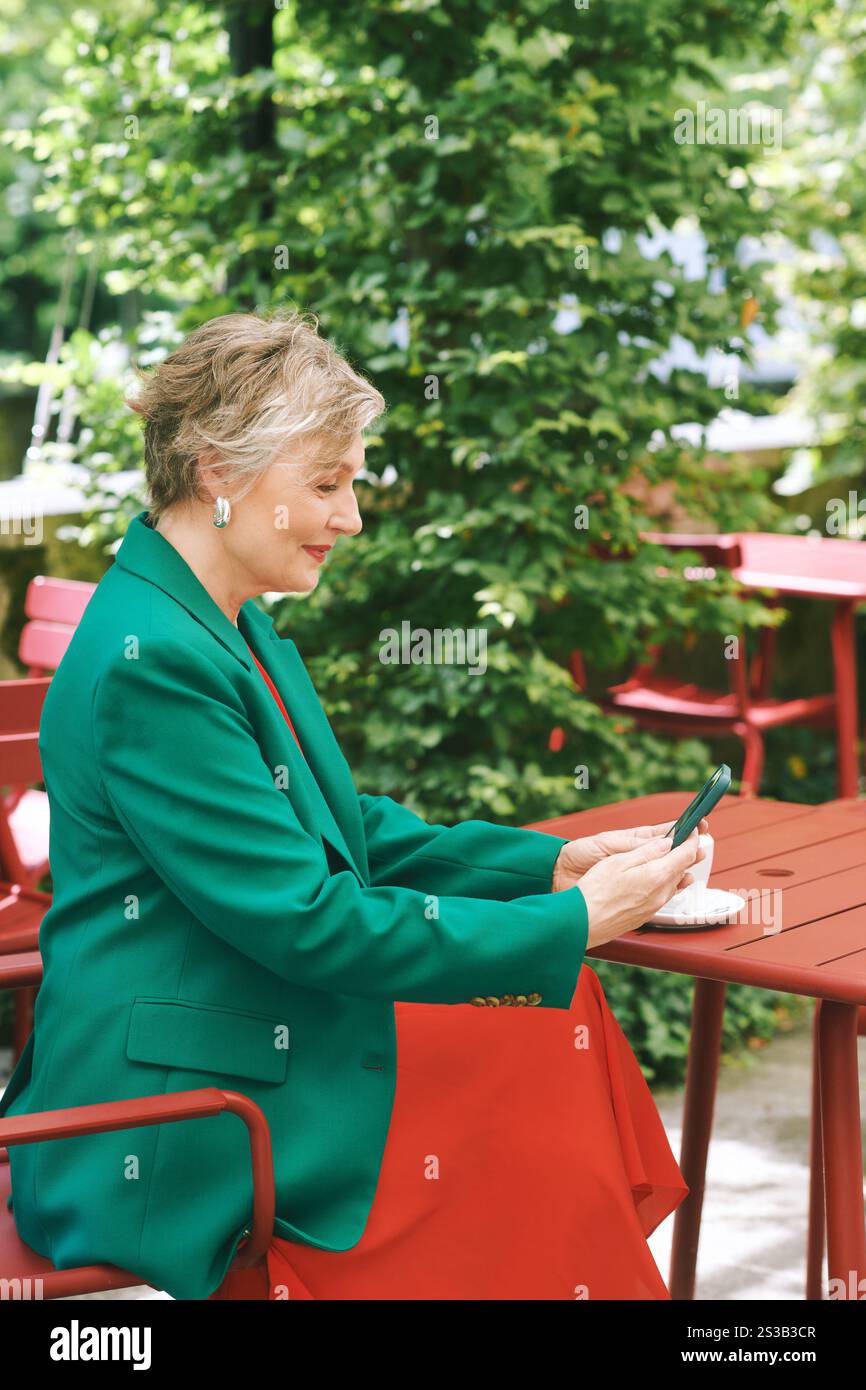 Outdoor portrait of pretty middle age 55 - 60 year old woman relaxing in cafe using phone Stock ...