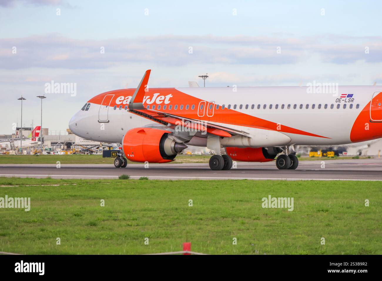 Orange and white easyjet airbus a320 taxiing on the runway at lisbon ...