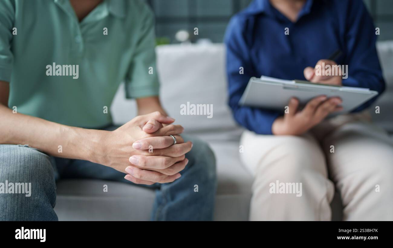 sad male sitting on sofa Patient discussing mental health issues with ...