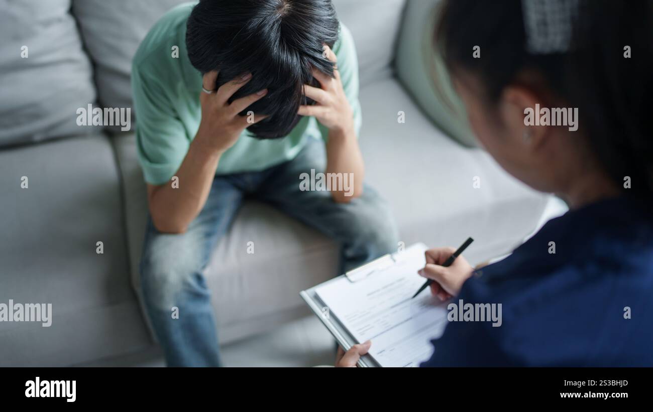 sad male sitting on sofa Patient discussing mental health issues with ...