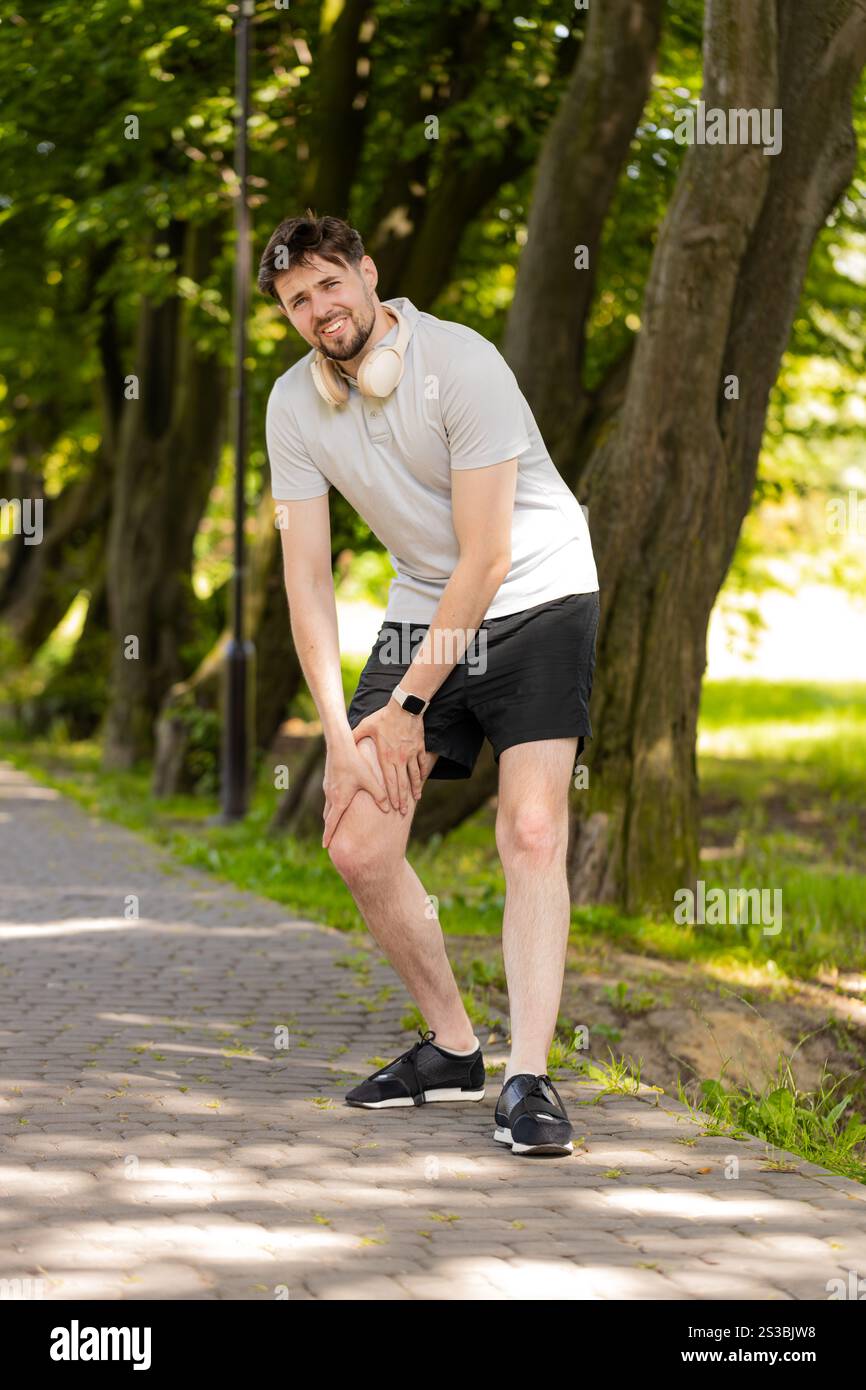 Young runner athlete with muscle pain. Man in shorts massaging ...