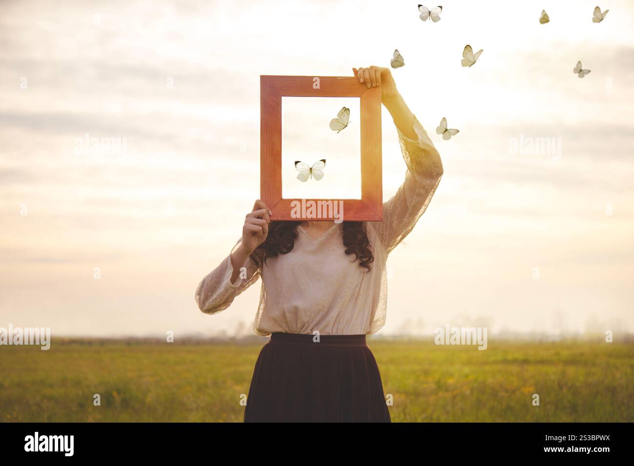 woman holding an empty frame that makes her face disappear reflecting ...