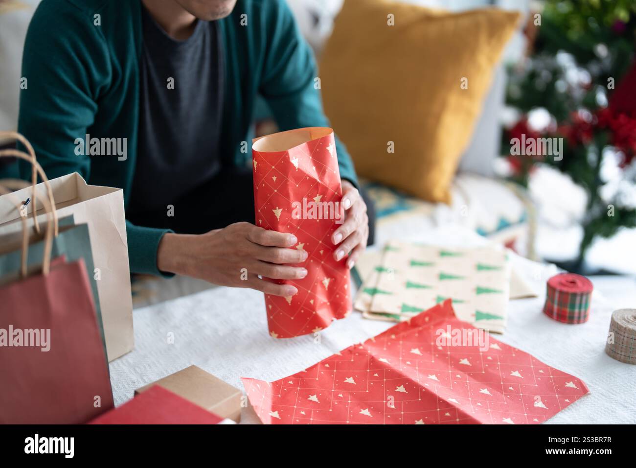Man in sweater wrapping christmas presents with eco paper girl packing ...