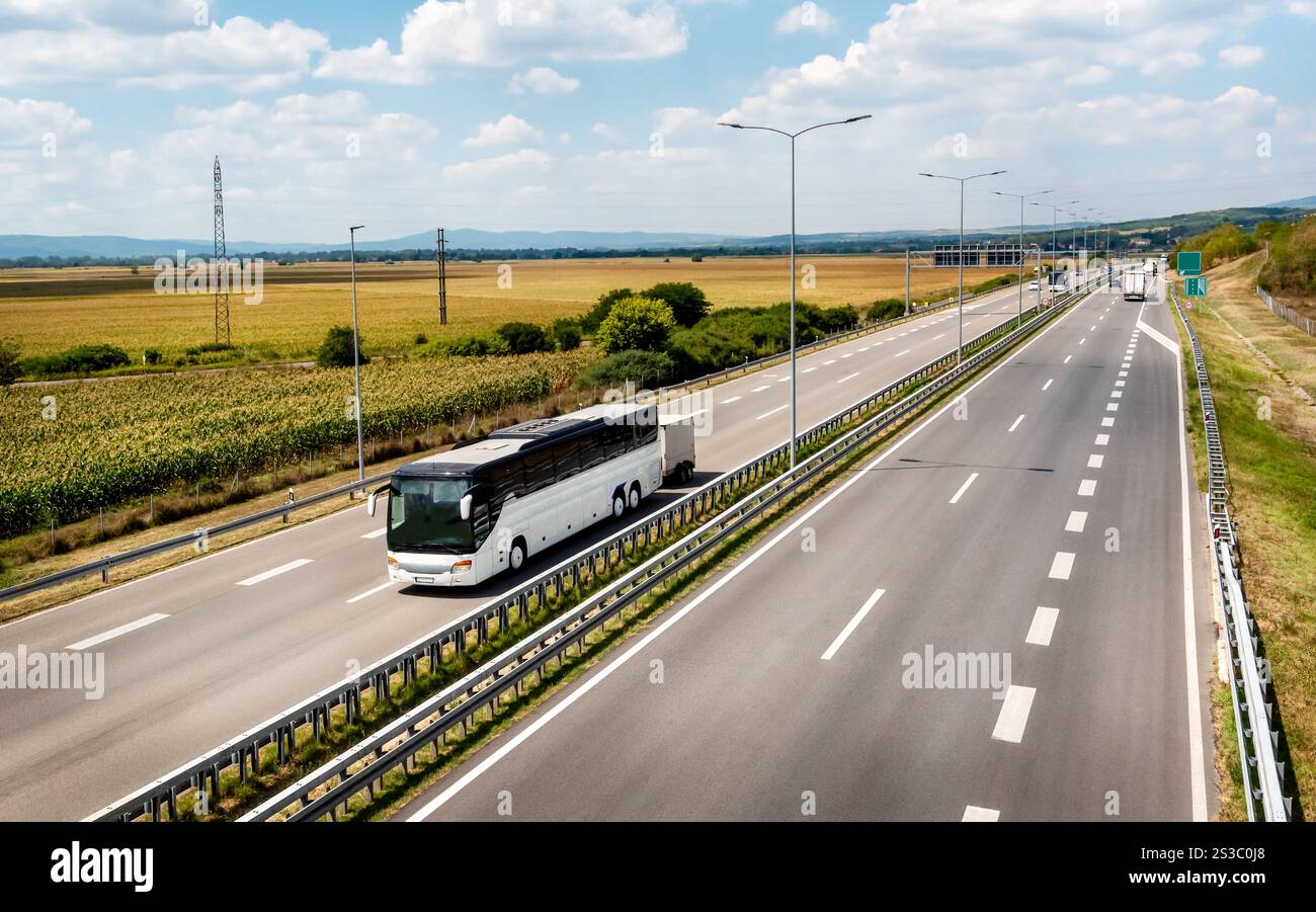 White Modern comfortable tourist bus driving through highway at bright ...