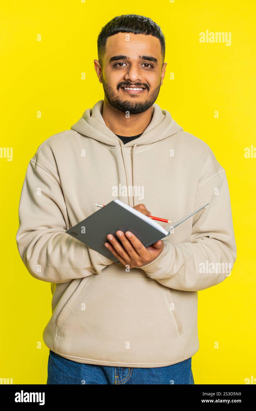 Thoughtful journalist young Indian man making notes, writing down ...