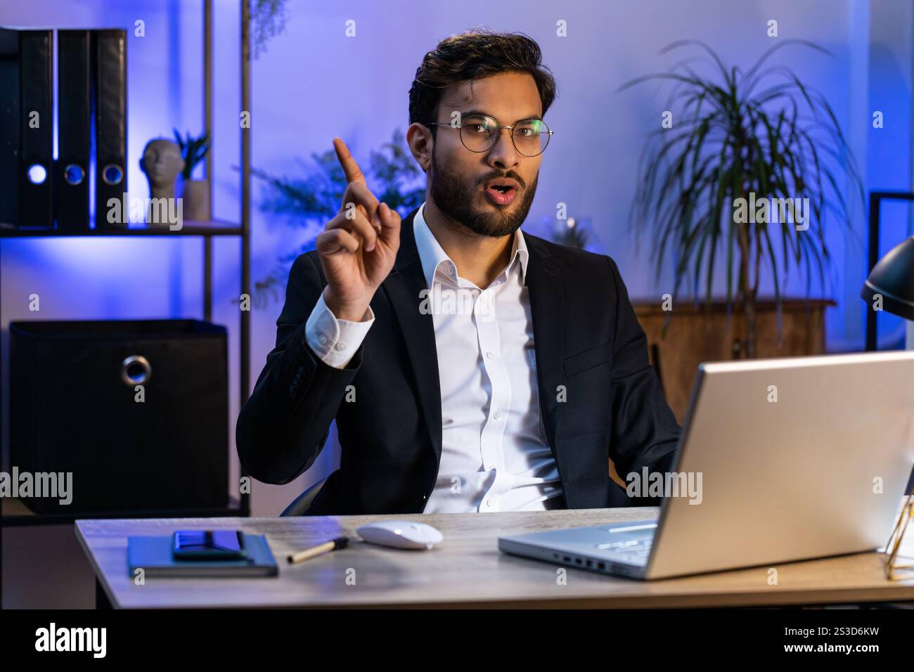 Indian young businessman working on laptop computer shakes finger and ...