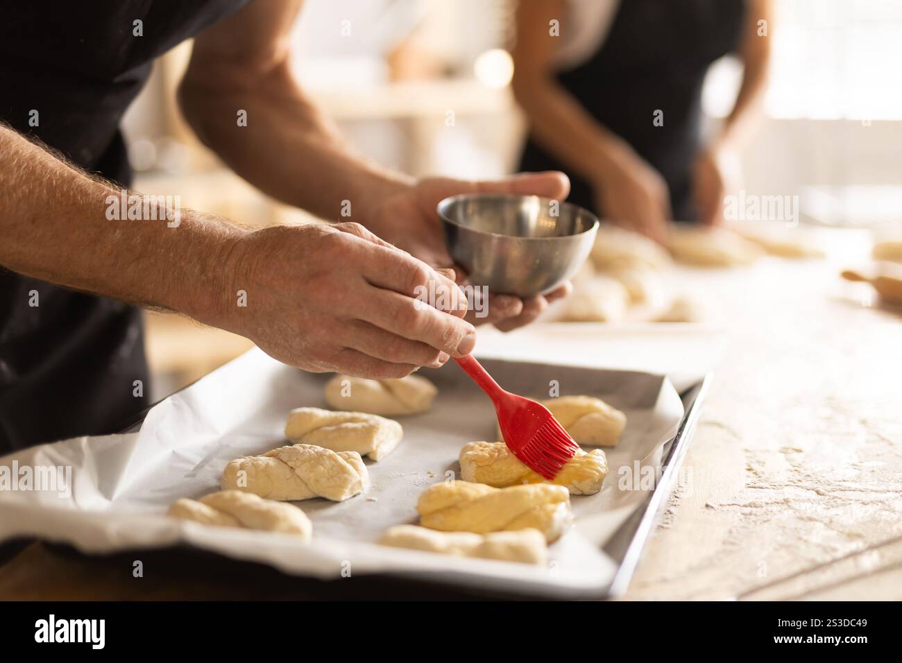 Baker's hands grease pieces of dough on baking sheet Stock Photo - Alamy