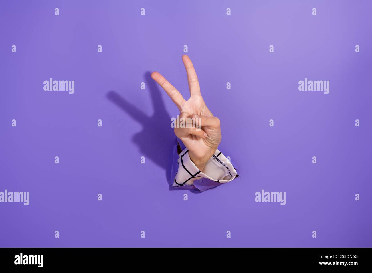 Victory hand gesture through a vibrant purple background expresses ...