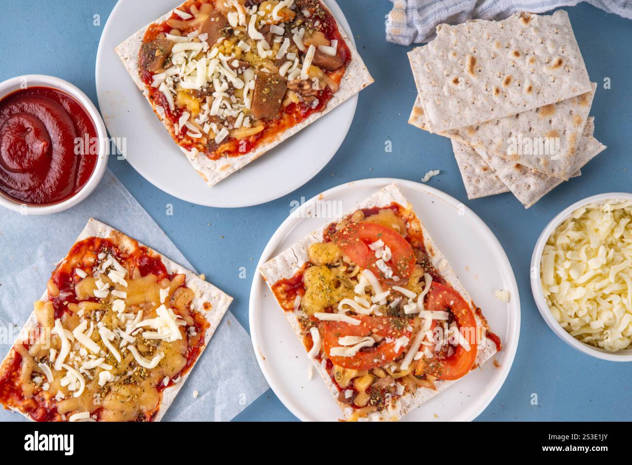 Matzah Pizza on light blue background with ingredients, cheese, tomato ...