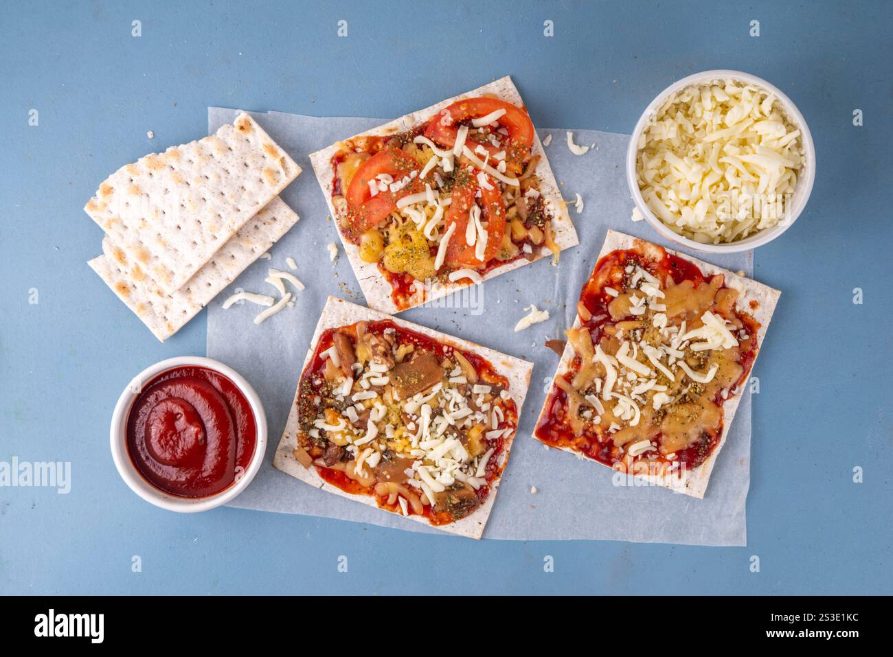 Matzah Pizza on light blue background with ingredients, cheese, tomato ...