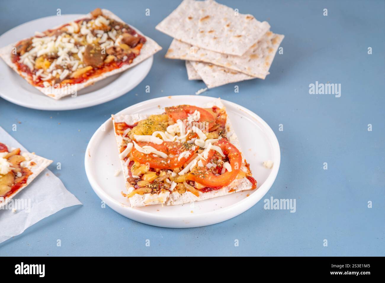 Matzah Pizza on light blue background with ingredients, cheese, tomato ...
