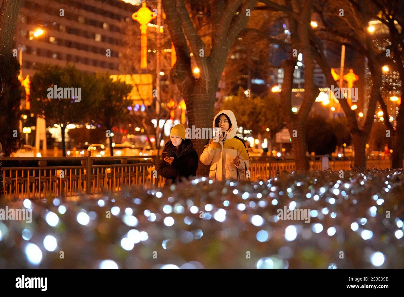 Two women walk beside lights along a street in Beijing, Thursday, Jan ...