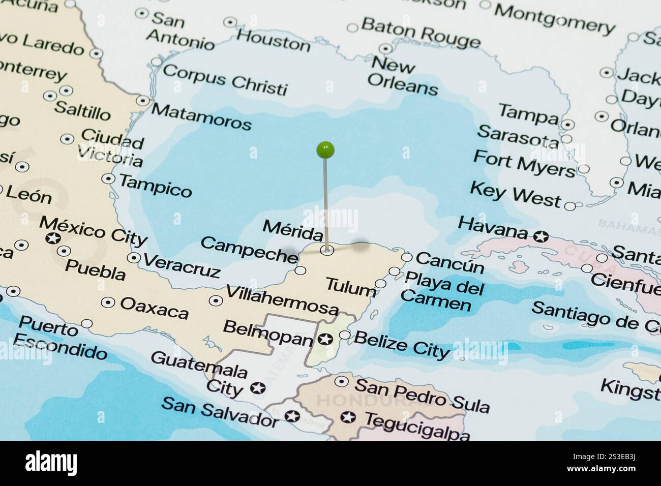 Macro photo of a green pin needle into Merida of Mexico political map ...